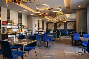 Um restaurante moderno com cadeiras estofadas em azul, um espaço de bar e um padrão de piso em herringbone.