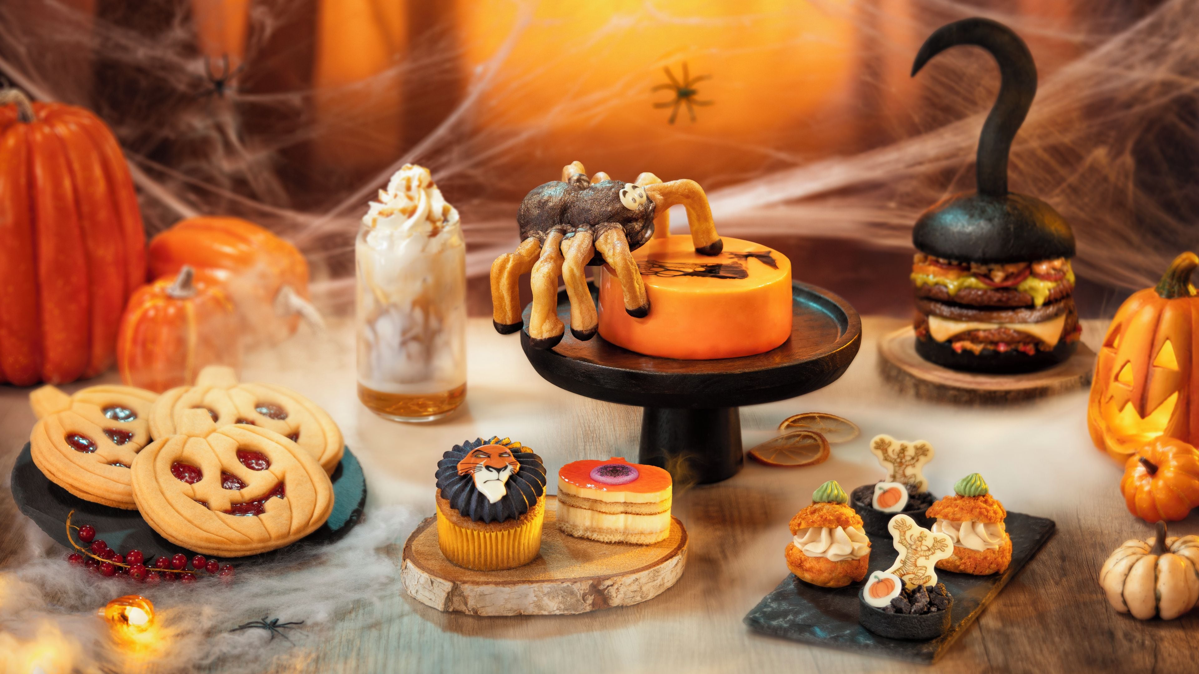Diversas sobremesas e doces com tema de Halloween sobre uma mesa.