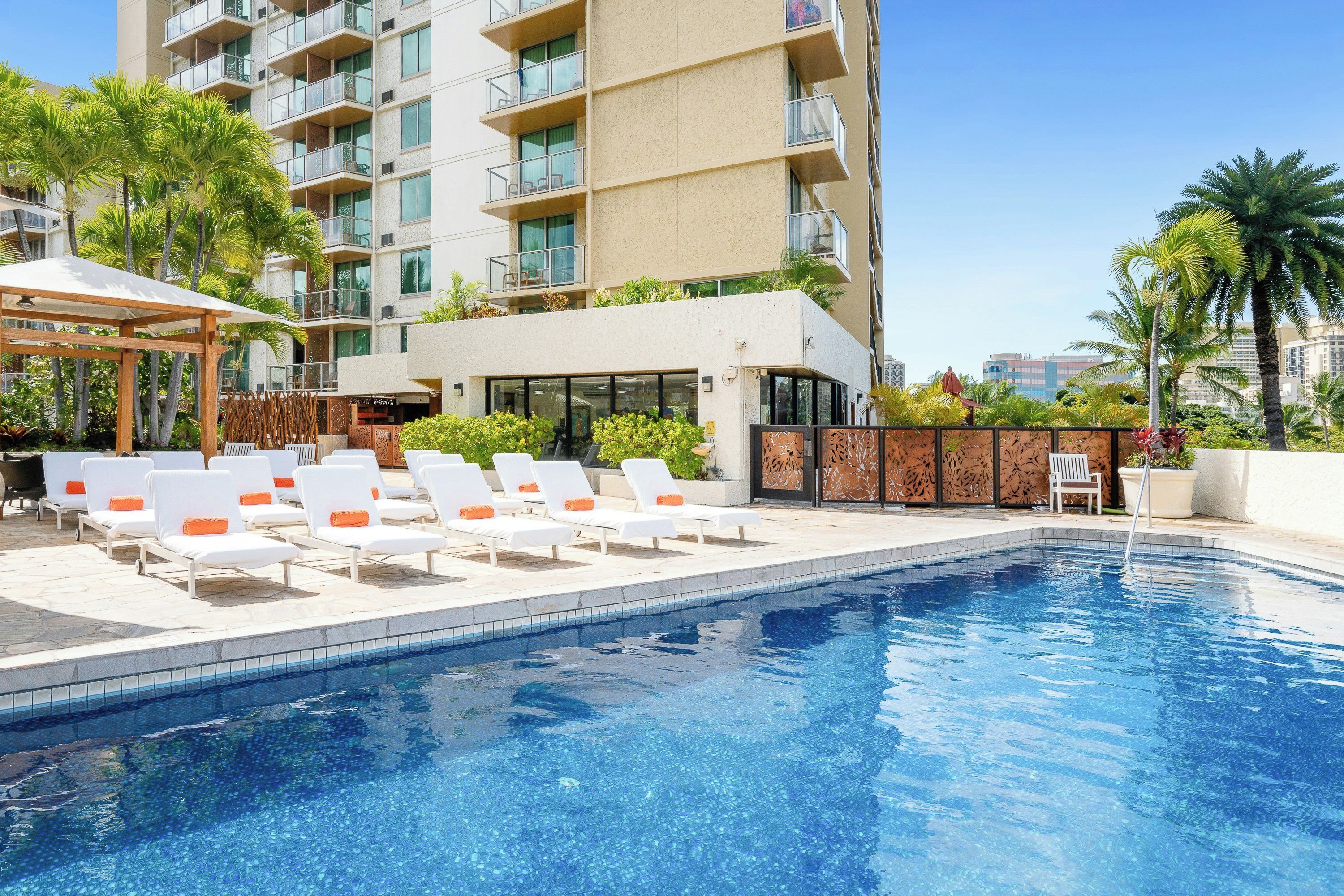 Piscina com espreguiçadeiras e área de estar coberta.