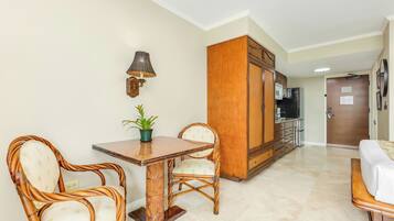 Quarto com mesa de jantar, cadeiras, planta em vaso, guarda-roupa e cozinha compacta.