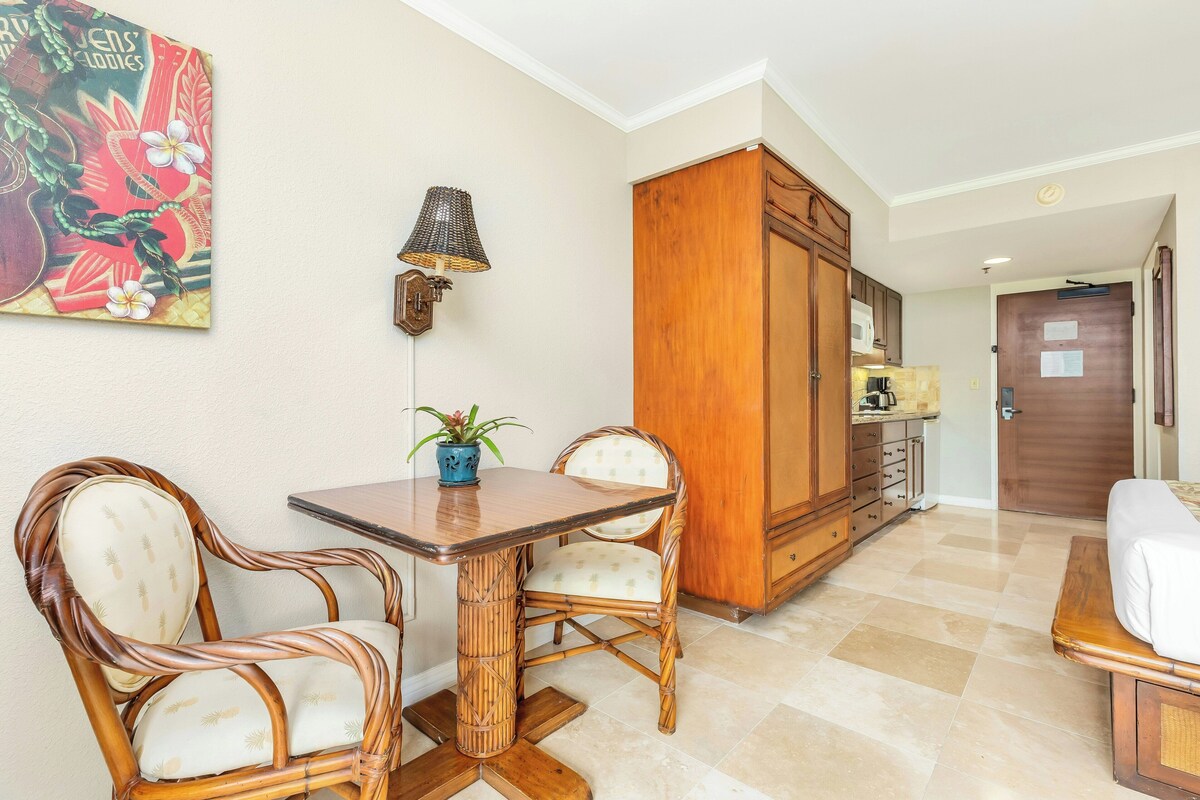 Uma área de refeições com mesa e cadeiras de madeira, luminária na parede e um armário.