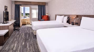 Quarto de hotel com duas camas, uma mesa, uma cadeira e uma televisão.
