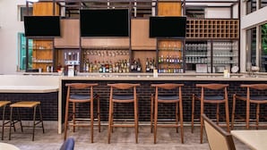 Uma área de bar com banquetas de madeira, um balcão com diversos frascos e copos, e um aviso indicando 'NO MINORS'.