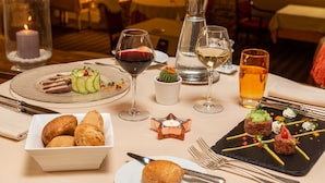 Uma mesa de jantar posta com diversos pratos, copos de vinho e uma vela.