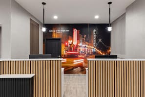 Uma área de recepção de hotel com um mural da paisagem urbana, divisórias de painéis de madeira e uma mesa Lenovo.