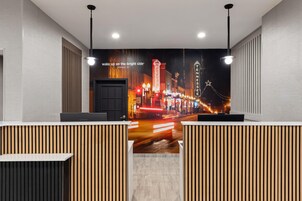 Uma área de recepção de hotel com um mural da paisagem urbana, divisórias de painéis de madeira e uma mesa Lenovo.