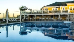 Um hotel com piscina, área de estar ao ar livre e um edifício de vários andares com varandas.