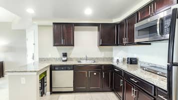 Cozinha moderna com armários escuros, eletrodomésticos de aço inoxidável e bancada de granito.