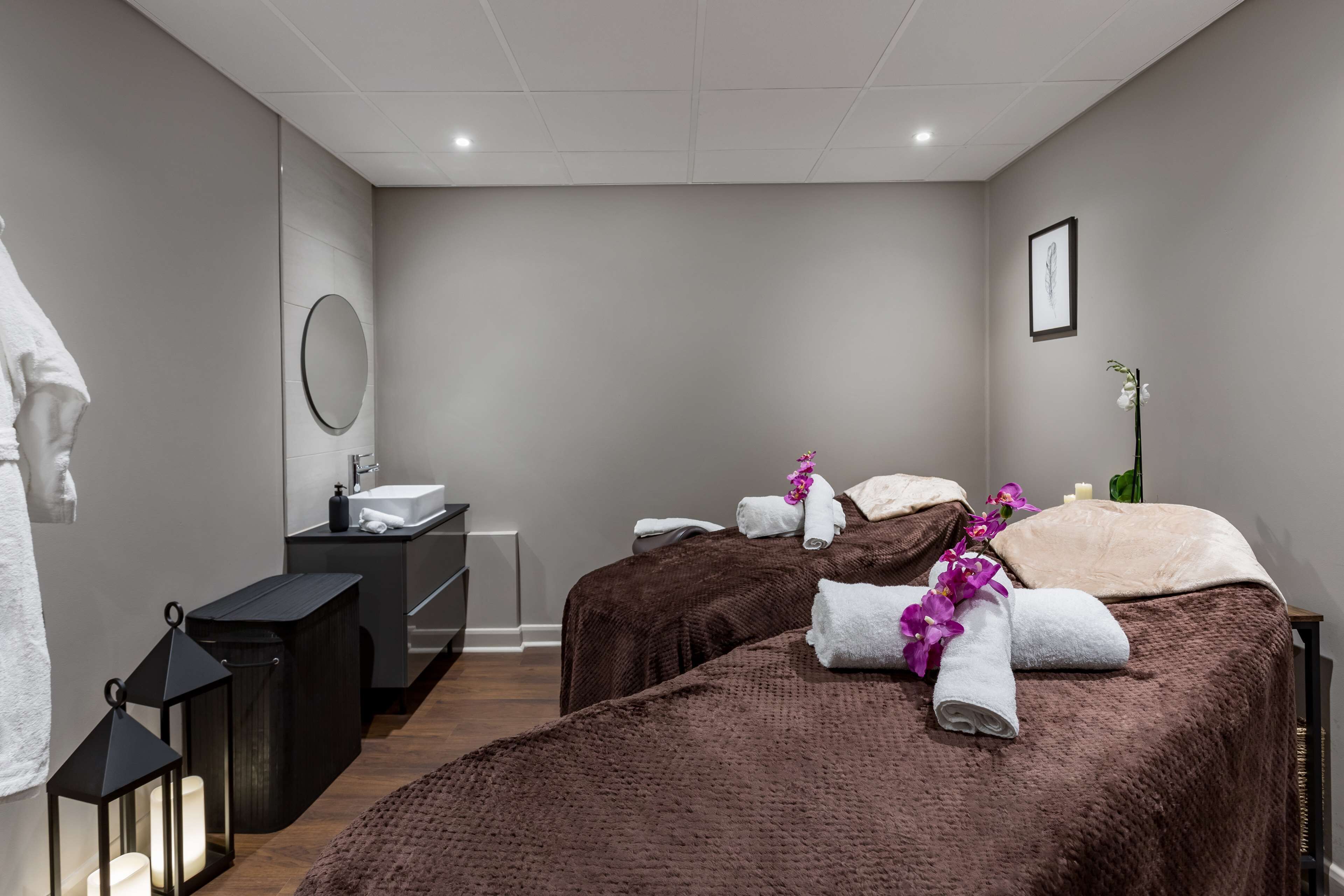 Uma sala de spa moderna com duas camas, uma pia e um espelho.