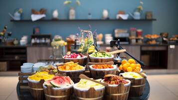 Buffet com diversas frutas e legumes em tigelas de madeira.