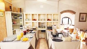 Disposição de buffet com diversos pontos de comida e bebida, incluindo uma exposição de frutas e um espaço para bebidas.