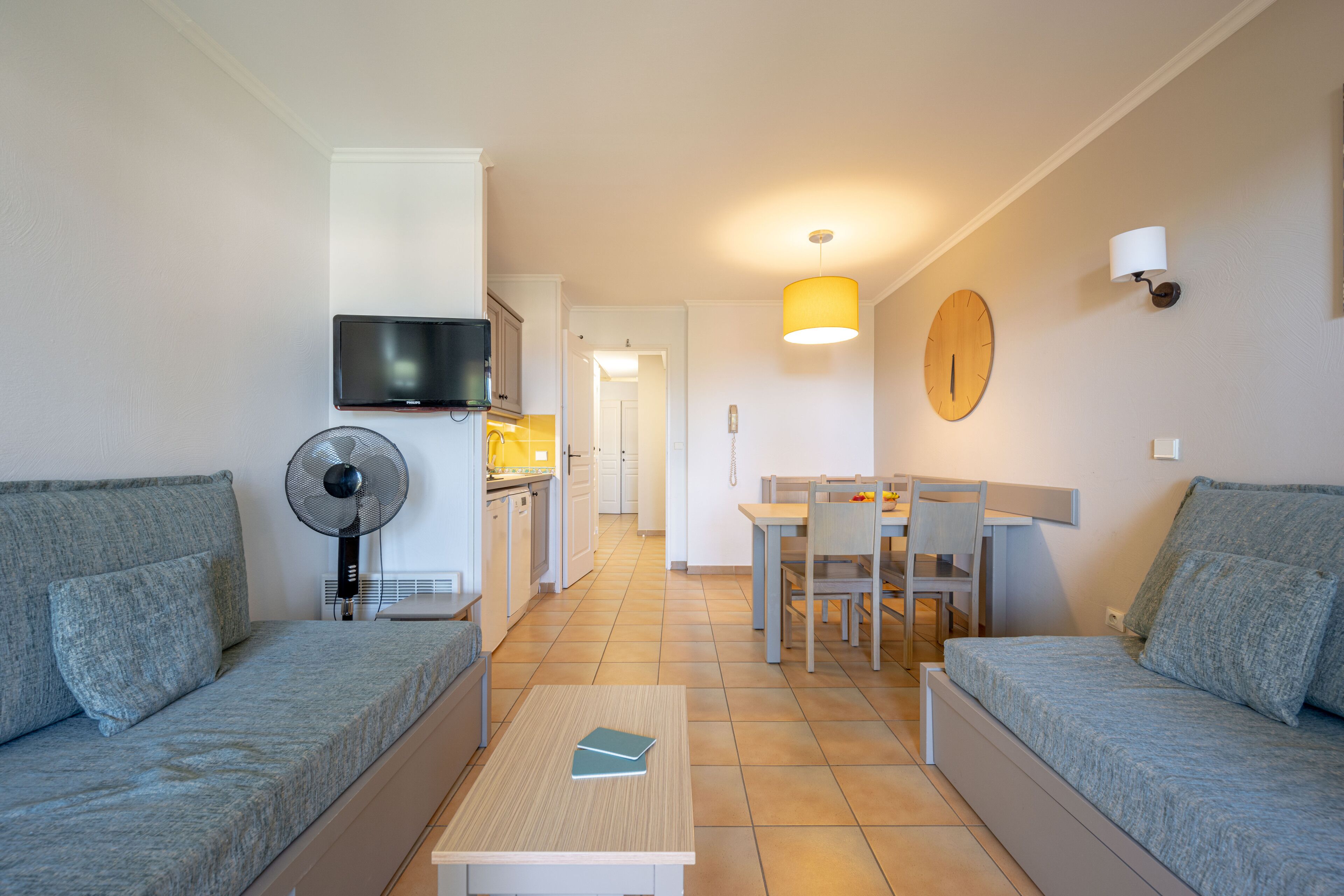 Uma sala de estar moderna com sofá, mesa de centro, TV e um espaço de jantar com cadeiras e mesa.