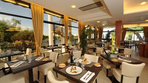 Um restaurante com várias mesas, cadeiras e uma escada que leva a uma área externa.