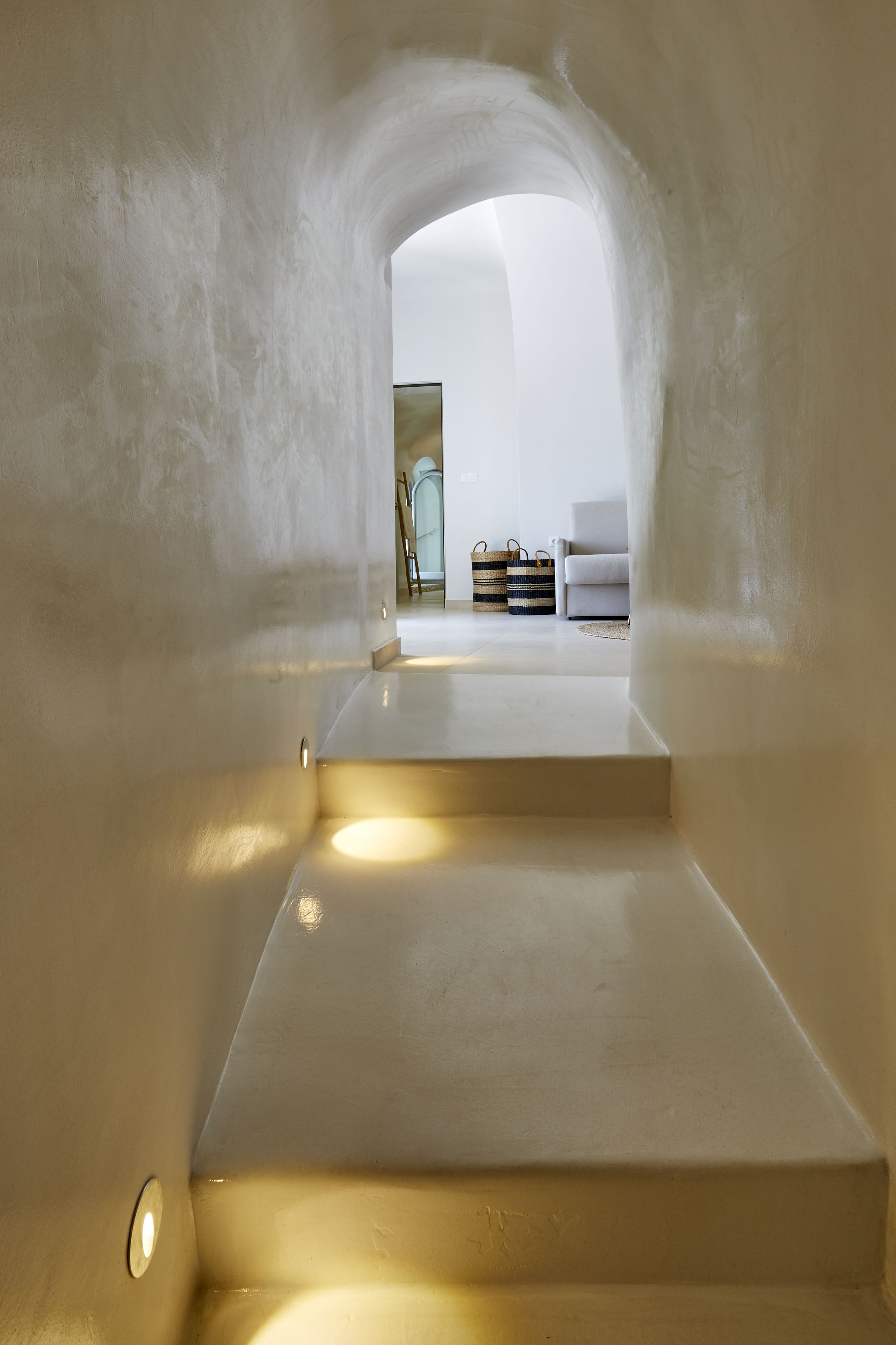 Um interior moderno com uma escada minimalista que leva a uma sala de estar.