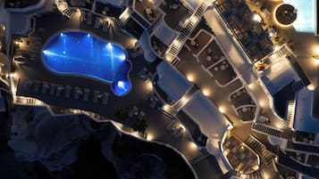 Vista aérea de um resort com uma grande piscina, diversas áreas de refeições e vários arranjos de assentos.