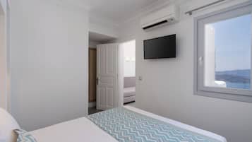 Quarto de hotel com uma cama, televisão fixada na parede e janela com vista.