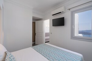 Quarto de hotel com uma cama, televisão fixada na parede e janela com vista.