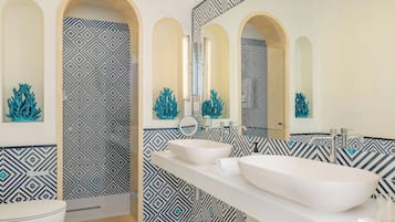 Banheiro com duas pias, um espelho e esculturas de coral decorativas.