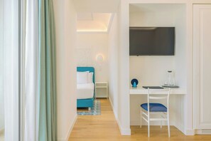 Quarto moderno com cama, escrivaninha e televisão.