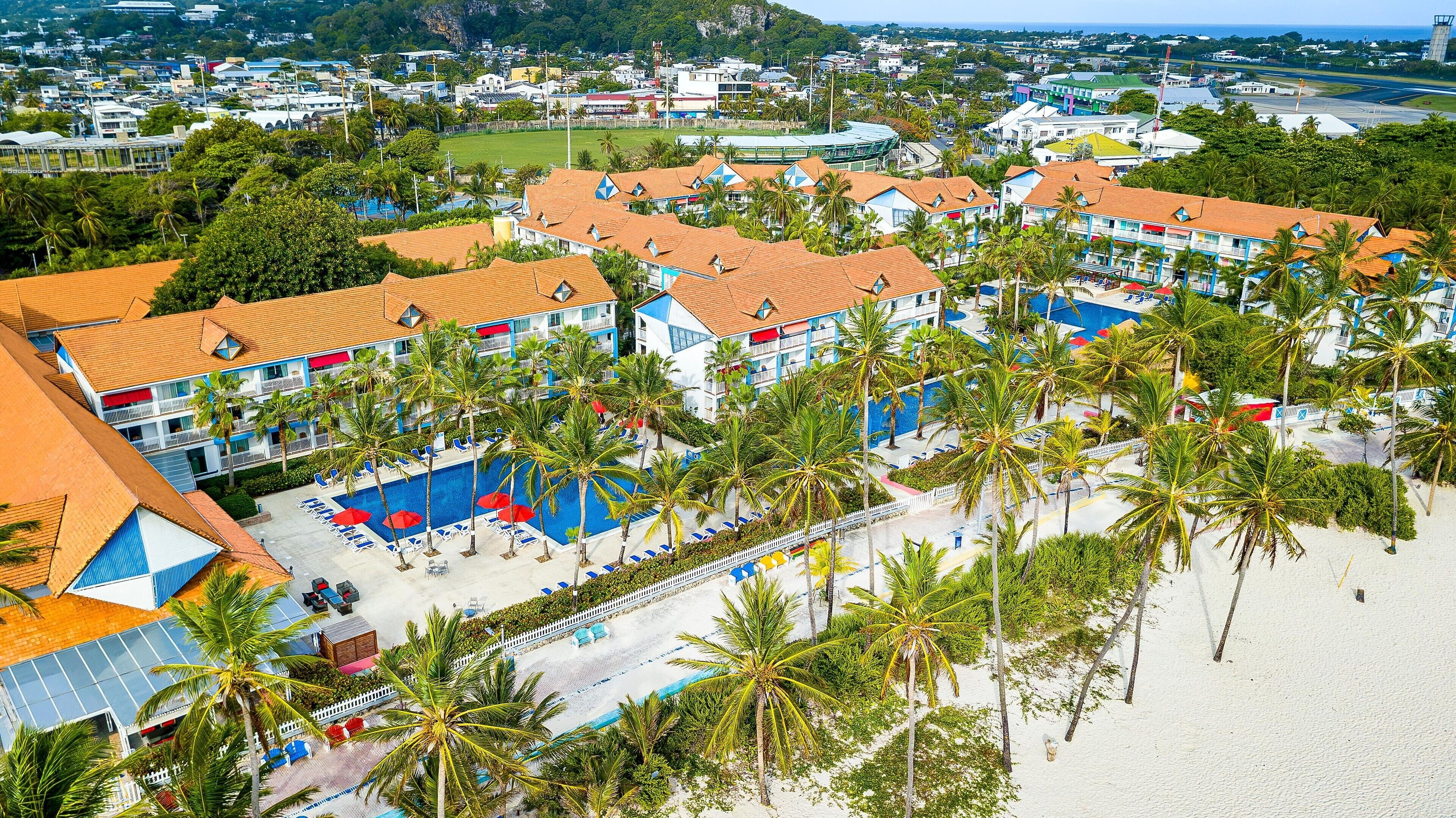 Um resort com vários edifícios, piscina e área de praia.