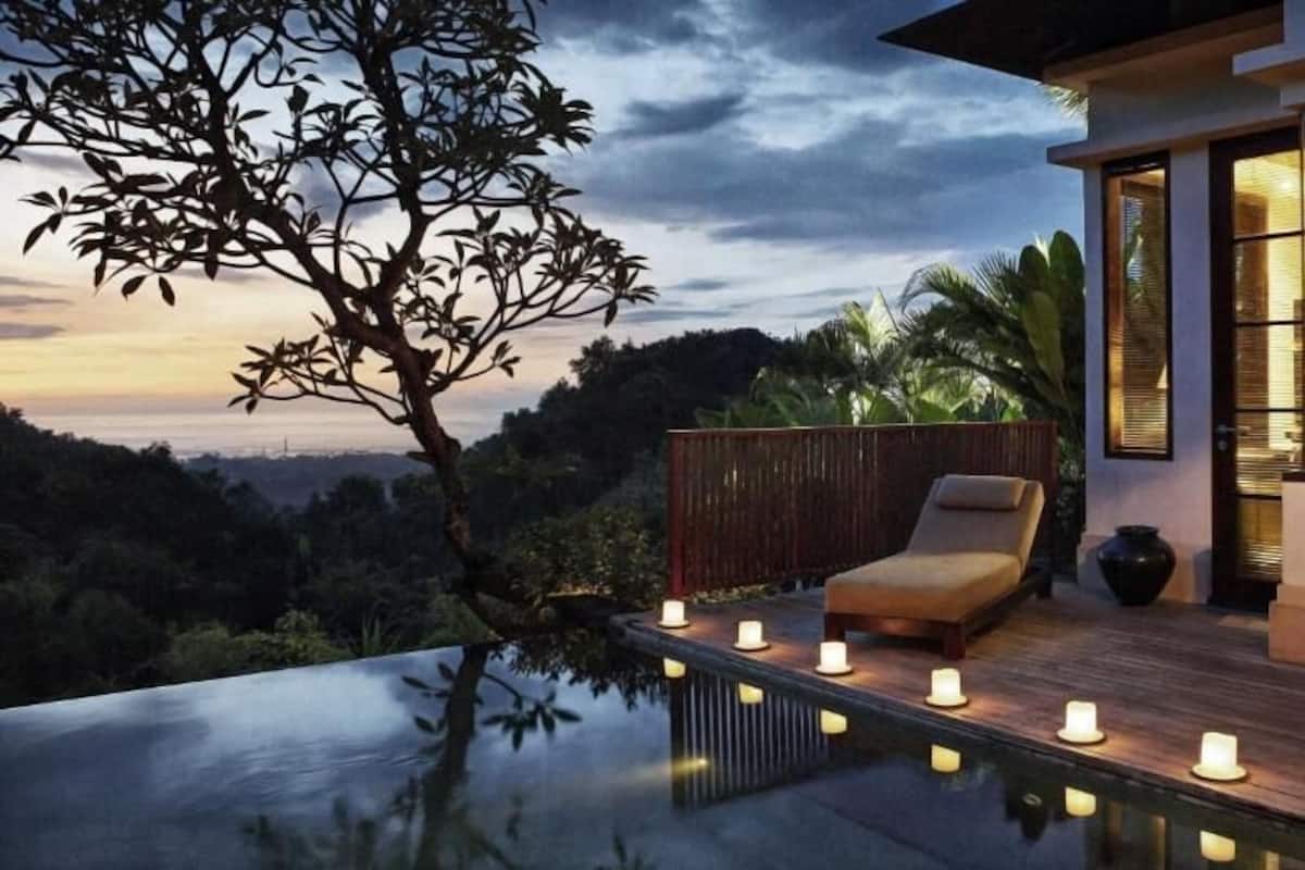 Uma área externa moderna com piscina, espreguiçadeira e velas.