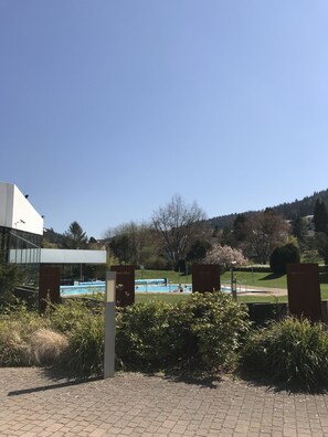 Um edifício moderno com piscina, rodeado por vegetação e colinas.