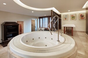 Um banheiro moderno com uma banheira grande, piso de madeira e um banco de madeira.