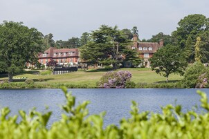 Um edifício grande e histórico com várias alas e um gramado bem cuidado na frente.