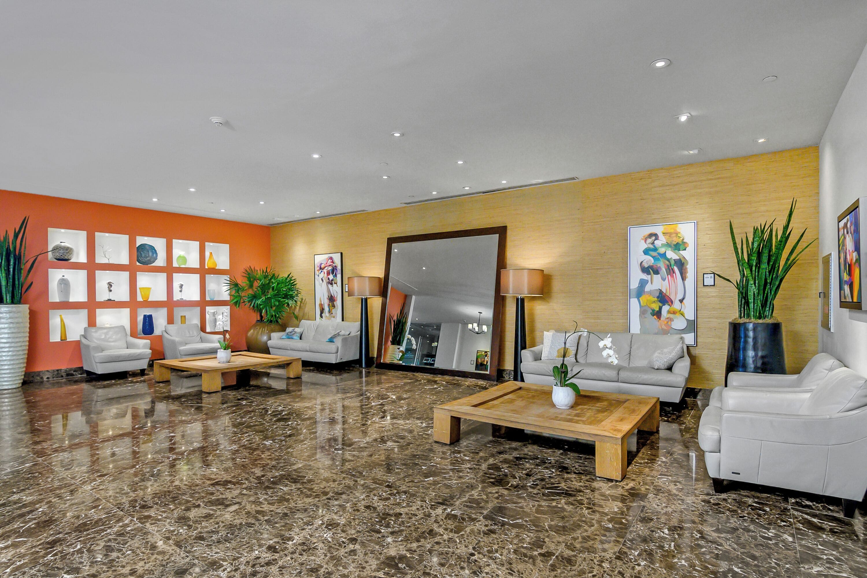 Um hall amplo com piso de mármore polido, vários espaços de estar e um espelho grande na parede.