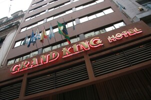 Exterior do Grand King Hotel, com seu nome iluminado em neon.
