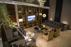 Uma sala de estar moderna com televisão, sofá, cadeiras, uma mesa de centro e uma estante.