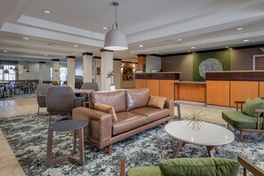 Um lobby moderno com um sofá de couro, uma mesa redonda e um balcão de recepção.