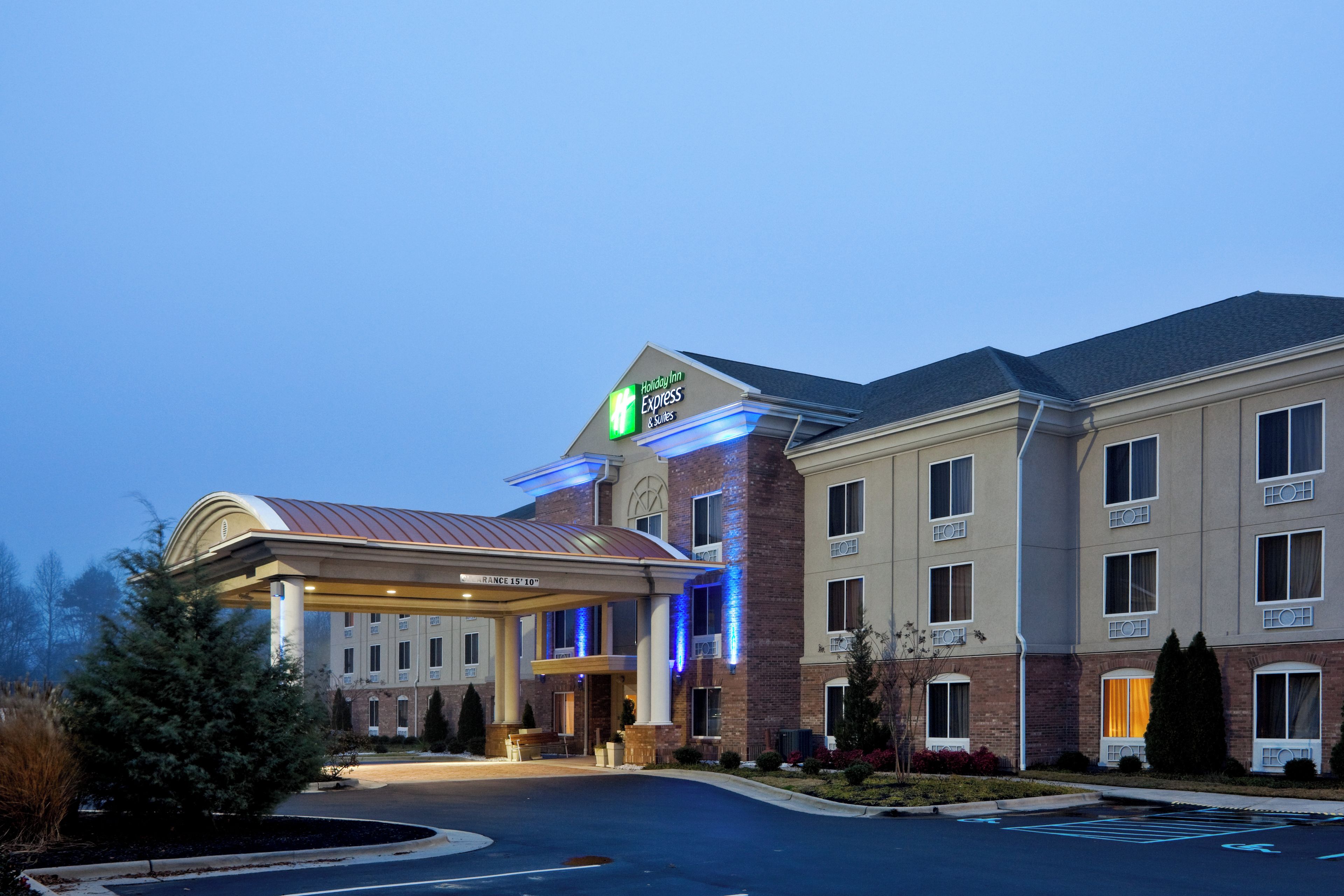 Um hotel Holiday Inn Express com entrada coberta, fachada de tijolos e estacionamento.