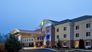 Um hotel Holiday Inn Express com entrada coberta, fachada de tijolos e estacionamento.