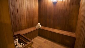 Uma sala de sauna com paredes, bancos e um banco de madeira com toalhas.
