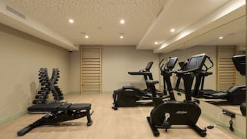 Uma academia com esteiras, um banco e halteres.