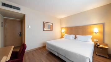 Quarto de hotel com cama grande, abajures, escrivaninha e uma cadeira.