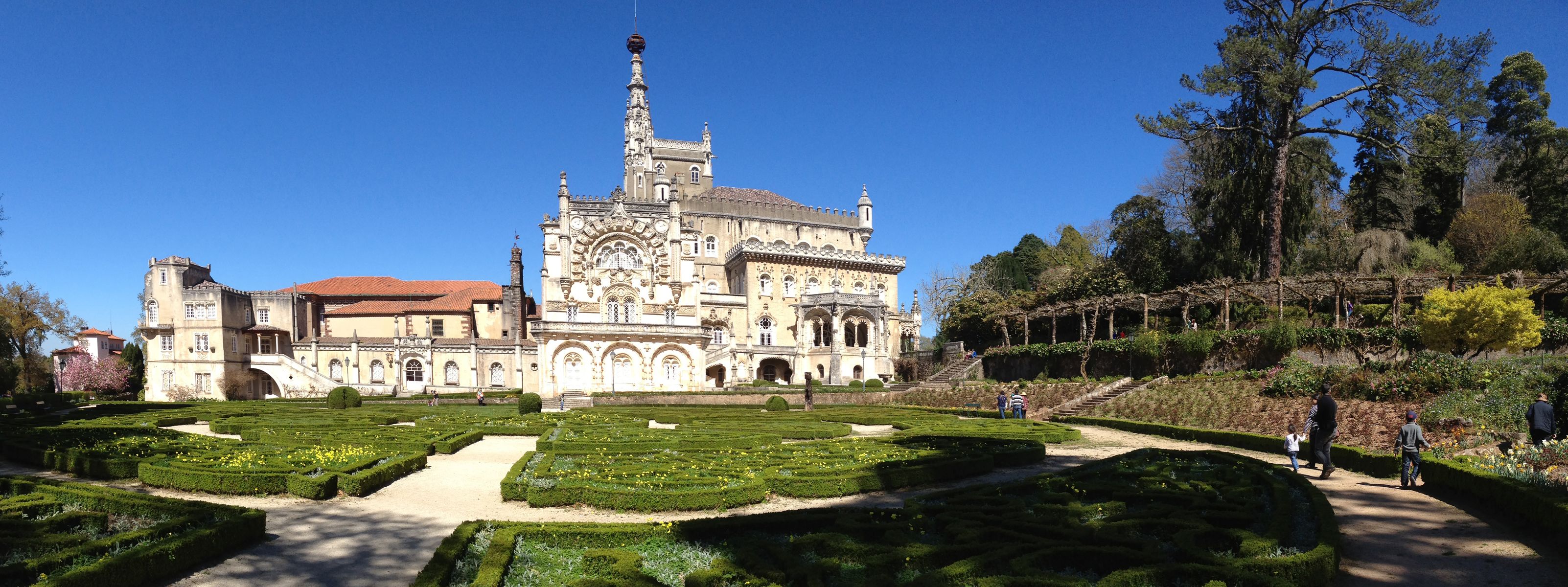 Um edifício histórico com uma torre central imponente e um jardim de layout simétrico.