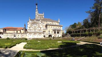 Um edifício histórico com uma torre central imponente e um jardim de layout simétrico.