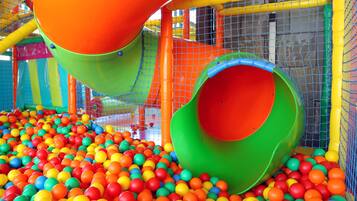 Uma área de recreação infantil colorida, com piscina de bolinhas e escorregadores.