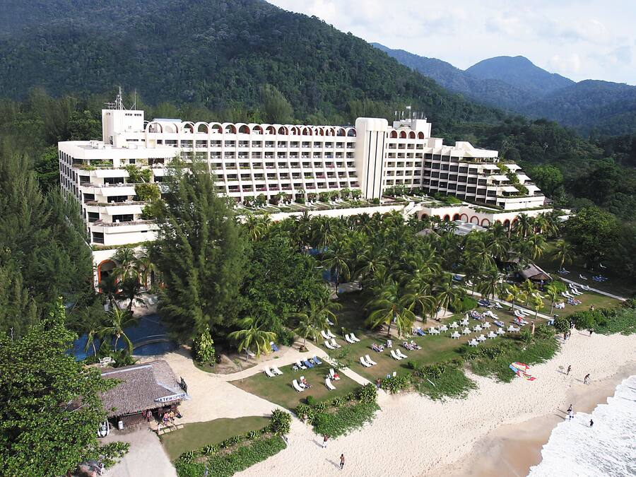 Um grande resort com vários edifícios, uma praia e palmeiras.