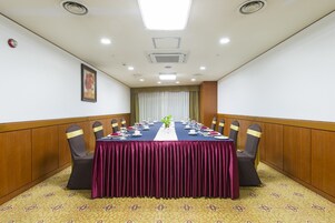 Uma sala de conferências com uma mesa comprida, cadeiras e um adorno decorativo.