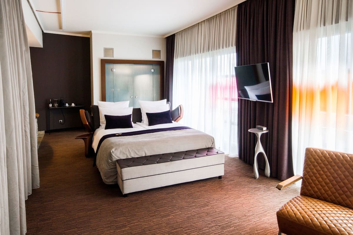 Quarto de hotel com cama, televisão, escrivaninha e cadeira.