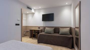Quarto de hotel moderno com uma cama, uma escrivaninha, uma cadeira e uma TV de tela plana fixada na parede.