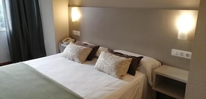 Quarto de hotel com cama, mesas de cabeceira e telefone.