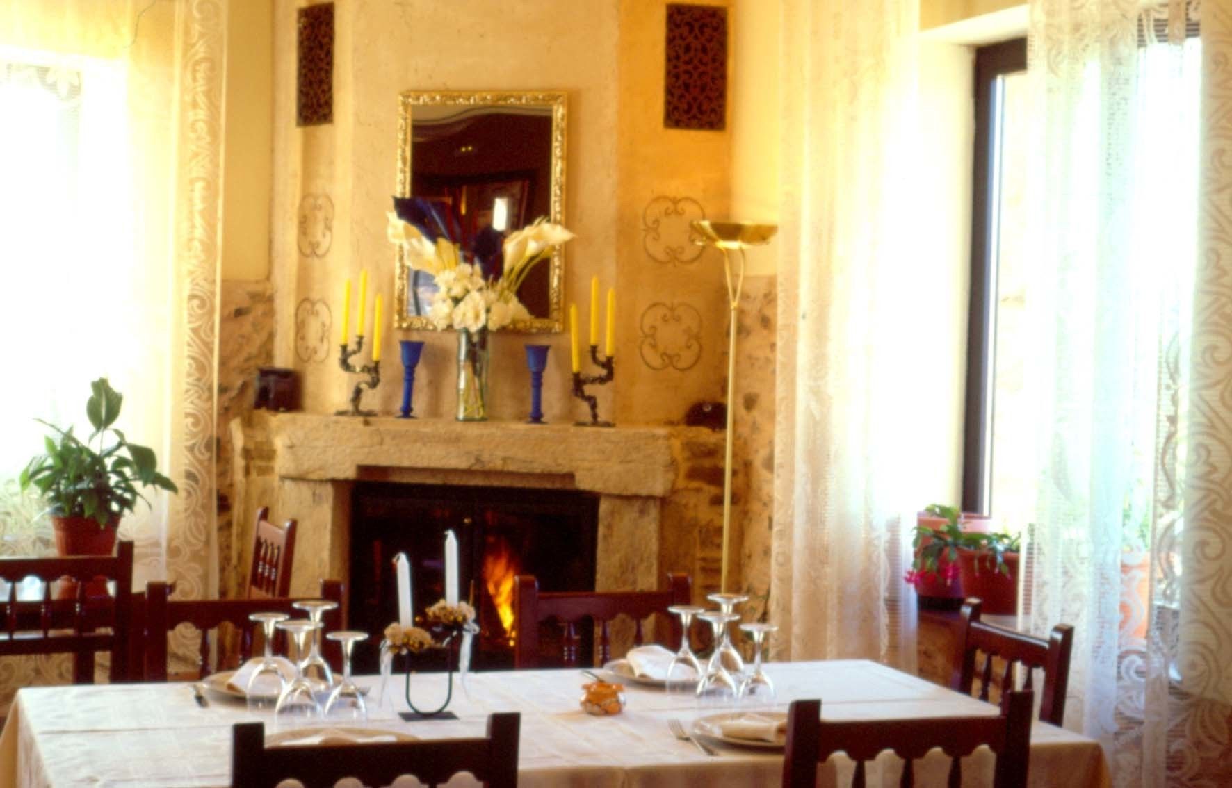 Uma sala de jantar com lareira, velas e mesa posta para quatro pessoas.