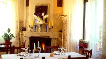 Uma sala de jantar com lareira, velas e mesa posta para quatro pessoas.