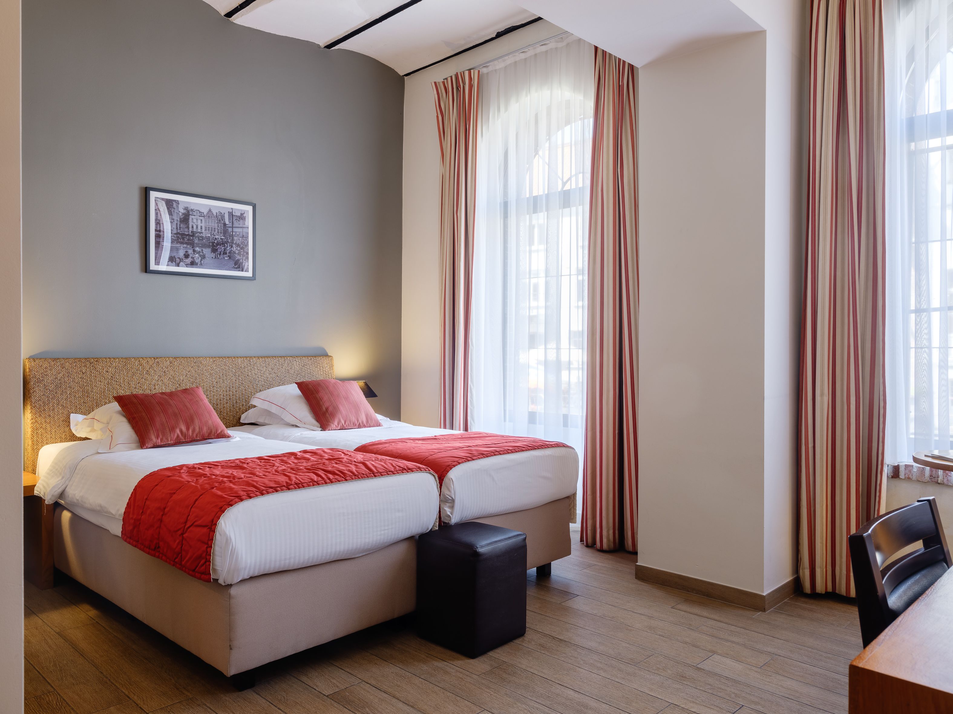 Quarto de hotel com uma cama grande, uma mesinha e uma cadeira.