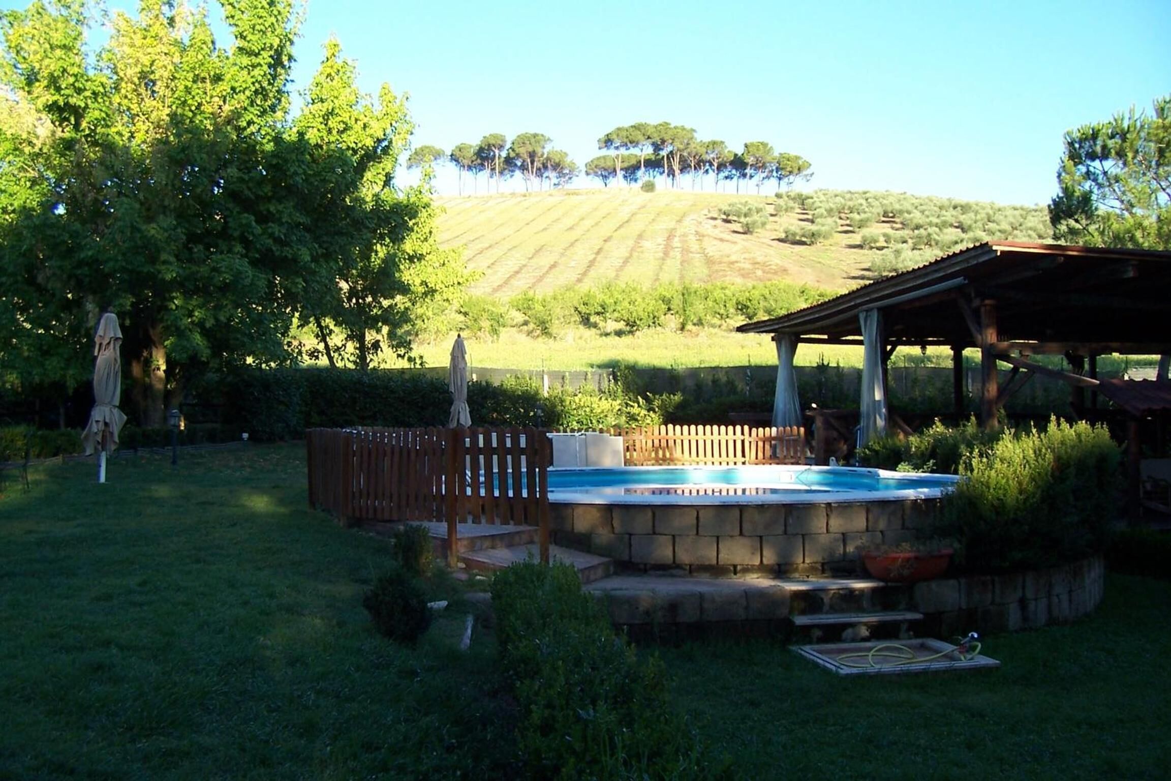 Um quintal com hidromassagem, deck de madeira e pérgola.