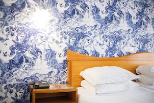 Quarto de hotel com cabeceira de madeira, roupa de cama branca e mesa de cabeceira com telefone.